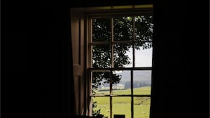 Quarto com uma grande janela com vista para uma paisagem verde.