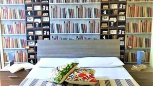 Um quarto com uma cama grande, roupa de cama listrada e uma estante cheia de livros.
