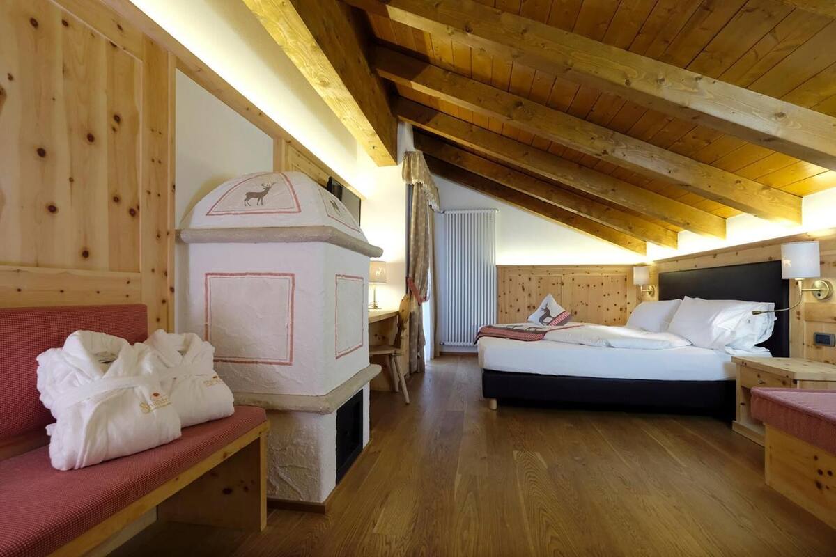 Quarto estilo cabana de madeira, com cama, um banco com toalhas e lareira.