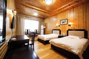 Quarto com painéis de madeira, duas camas, uma escrivaninha e uma cadeira.