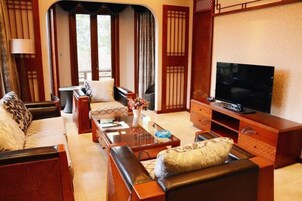 Uma sala de estar tradicional com sofá, mesa de centro, televisão e um vaso decorativo.