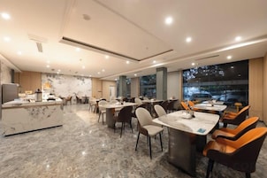 Uma sala de jantar moderna com piso de mármore, várias mesas e cadeiras, e uma grande janela que oferece uma vista.