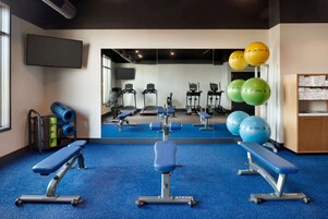 Uma academia com equipamentos de ginástica, bancos e bolas de exercício.