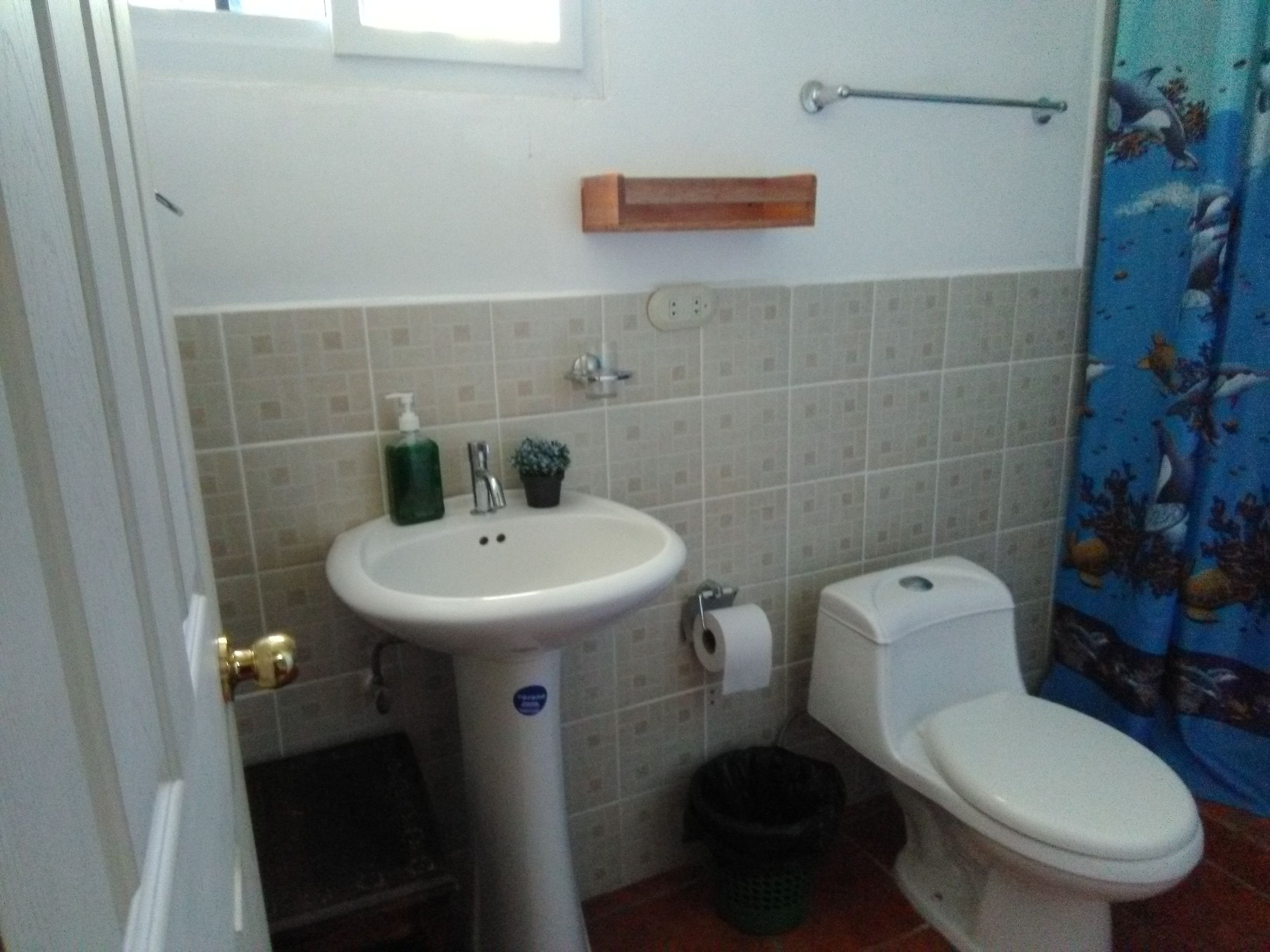 Casa de banho com lavatório, sanita e um pequeno contentor de lixo.