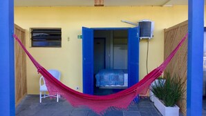 Quarto com rede, cama, janela e ar condicionado.