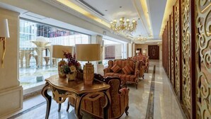 Um hall espaçoso com um lustre imponente, móveis elegantes e grandes janelas.