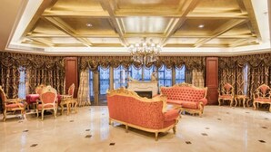 Um quarto amplo com mobiliário requintado, um lustre e uma lareira.