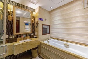 Casa de banho com um espelho grande, duas pias, uma banheira e um porta-toalhas.