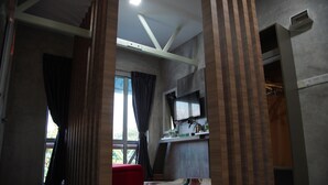 Quarto moderno com uma janela grande, um banquinho vermelho e uma área de kitchenette.