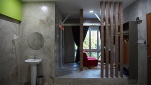 Casa de banho com lavatório, espelho e uma cadeira vermelha ao fundo.