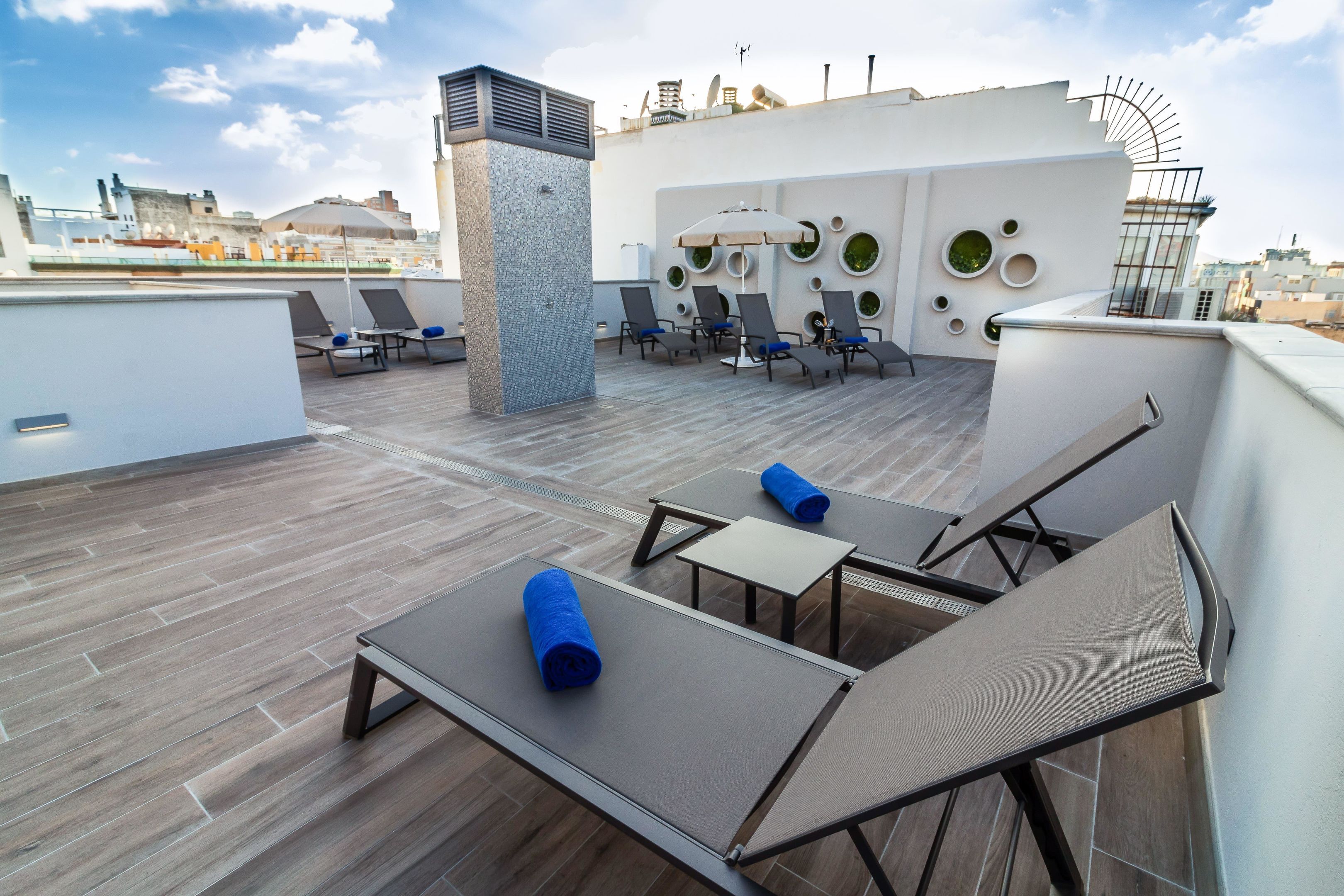 Terraço no telhado com cadeiras de descanso, uma mesa e uma parede decorativa.