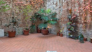 Pátio com plantas em vasos e muro de tijolos.