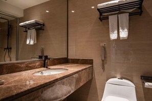 Uma casa de banho moderna com lavatório de mármore, sanita e espelho.
