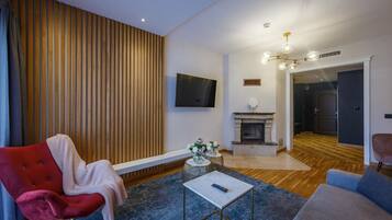 Uma sala de estar moderna com uma poltrona vermelha, um sofá, uma lareira e uma televisão na parede.