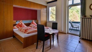 Quarto com cama, mesa, cadeiras, janela e vista para o exterior.
