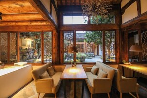 Interior tradicional em estilo japonês, com tatames, uma mesa de madeira baixa e vista para um jardim por grandes janelas.