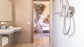 Uma casa de banho moderna com lavatório, espelho e chuveiro.