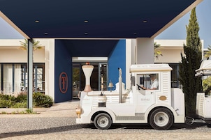 Um food truck de estilo antigo estacionado em frente a um edifício com entrada azul e um letreiro que diz 'PRIVATE TRANSPORT'.