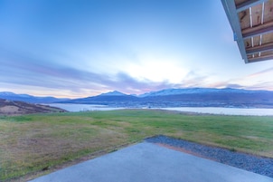 Vista de uma paisagem montanhosa com um lago e uma cidade ao longe.