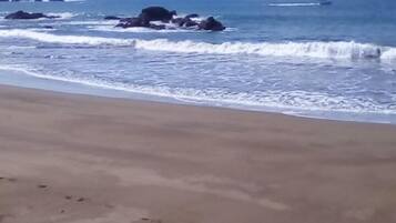 Uma praia com ondas e rochas ao longe.