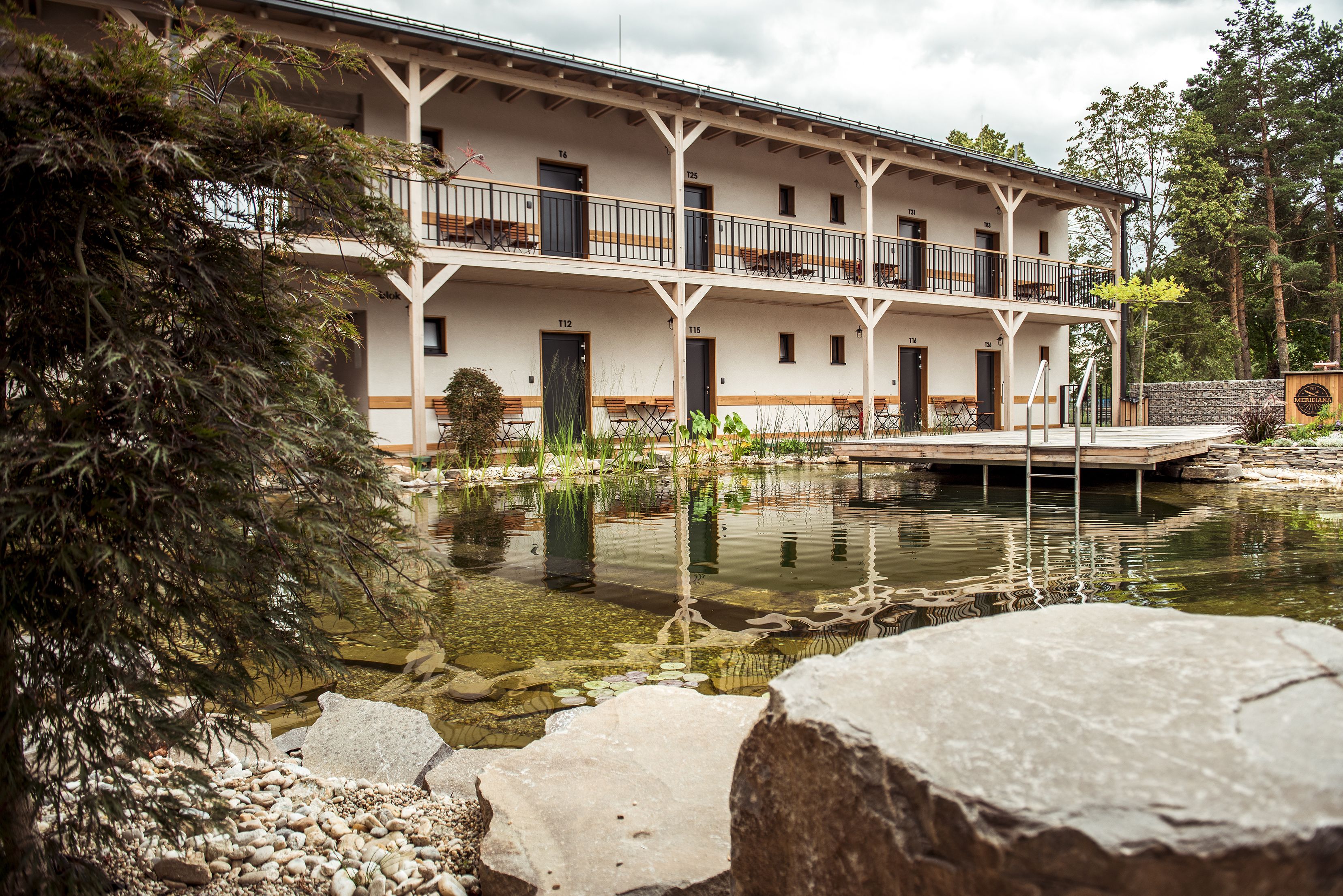 Um edifício de vários andares com varandas, um lago e um cais.