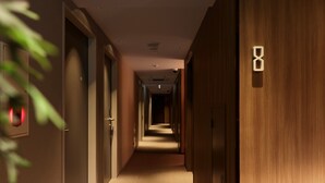 Corredor de hotel com paredes de madeira, piso coberto por carpete e placa com o número 8 à direita.