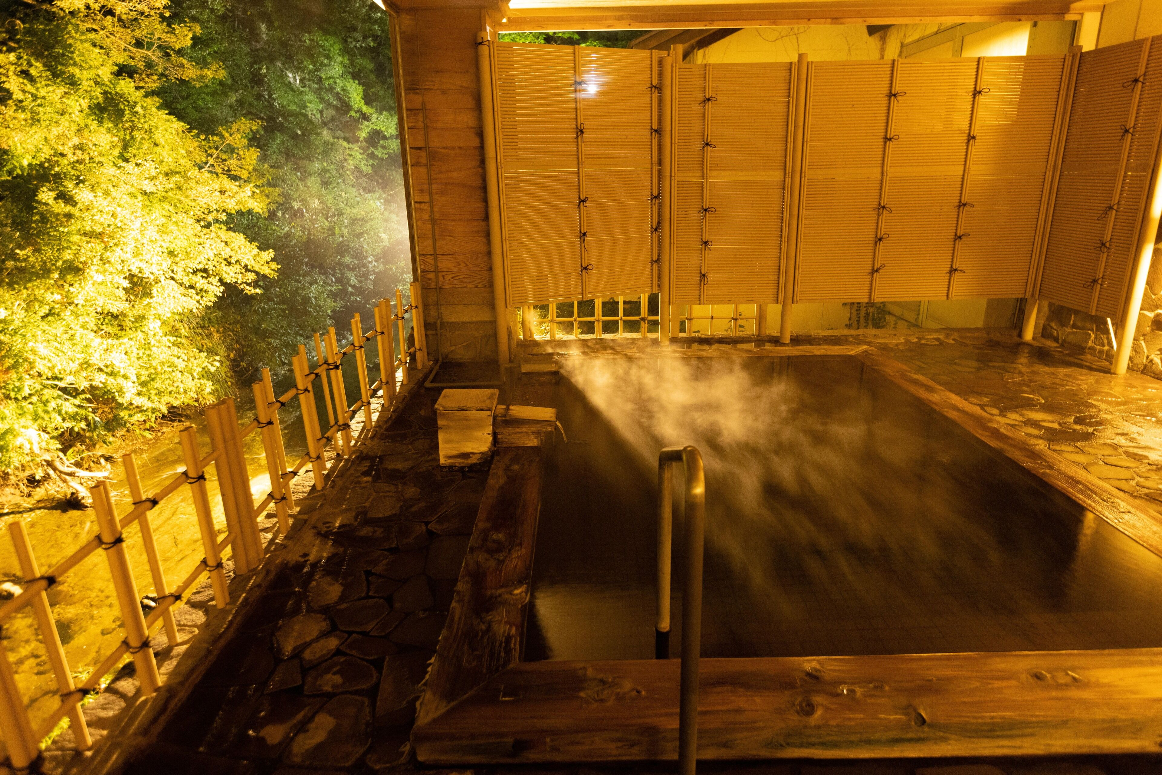Um onsen japonês tradicional com bancos de madeira e uma parede de pedra.