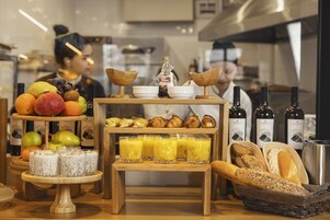Um buffet de café da manhã com frutas, pastelaria e sucos.