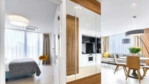 Quarto de hotel moderno com cama, área de jantar e cozinha.