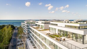 Um hotel moderno com vários andares, janelas amplas e vista para o mar.