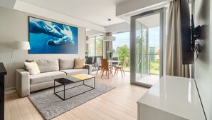 Uma sala de estar moderna com um sofá, mesa de centro e uma televisão grande.