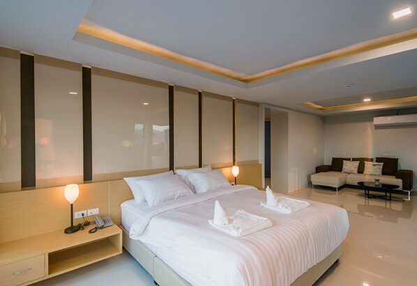 Quarto de hotel moderno com uma cama grande, mesas de cabeceira, um sofá e uma mesa de centro.
