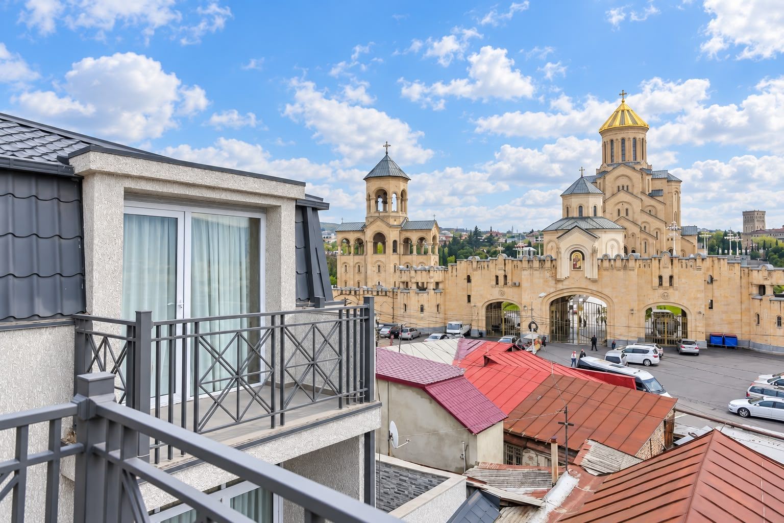 Vista de um edifício com uma entrada ampla e uma torre de sino, com veículos estacionados na frente.
