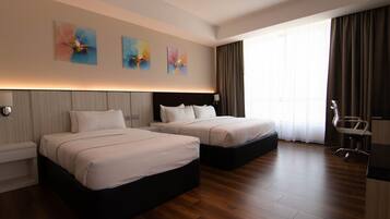 Quarto de hotel com duas camas, uma escrivaninha, uma cadeira e obras de arte na parede.