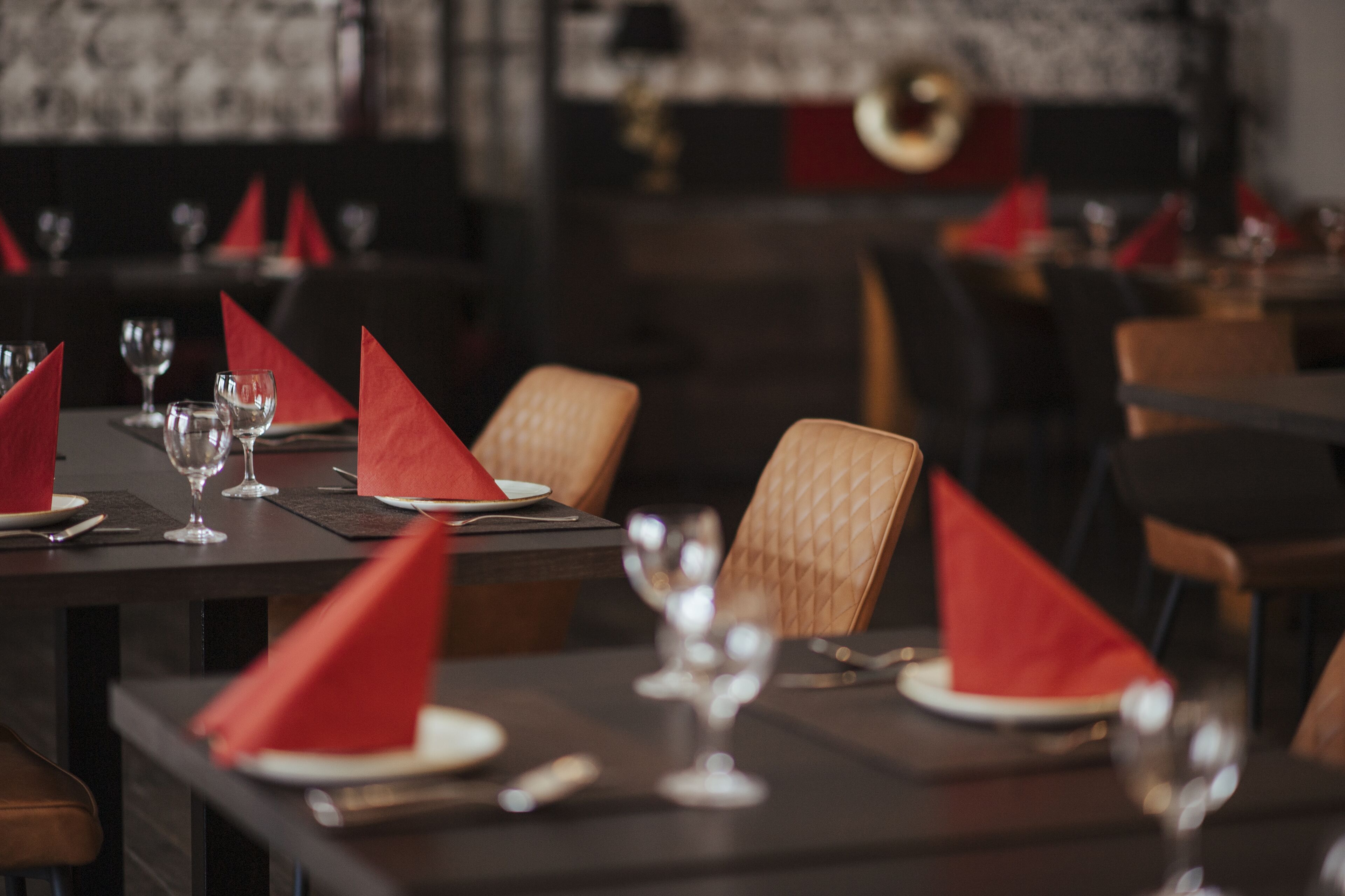 Ambiente de restaurante com mesas montadas para refeição, incluindo pratos, copos e guardanapos.