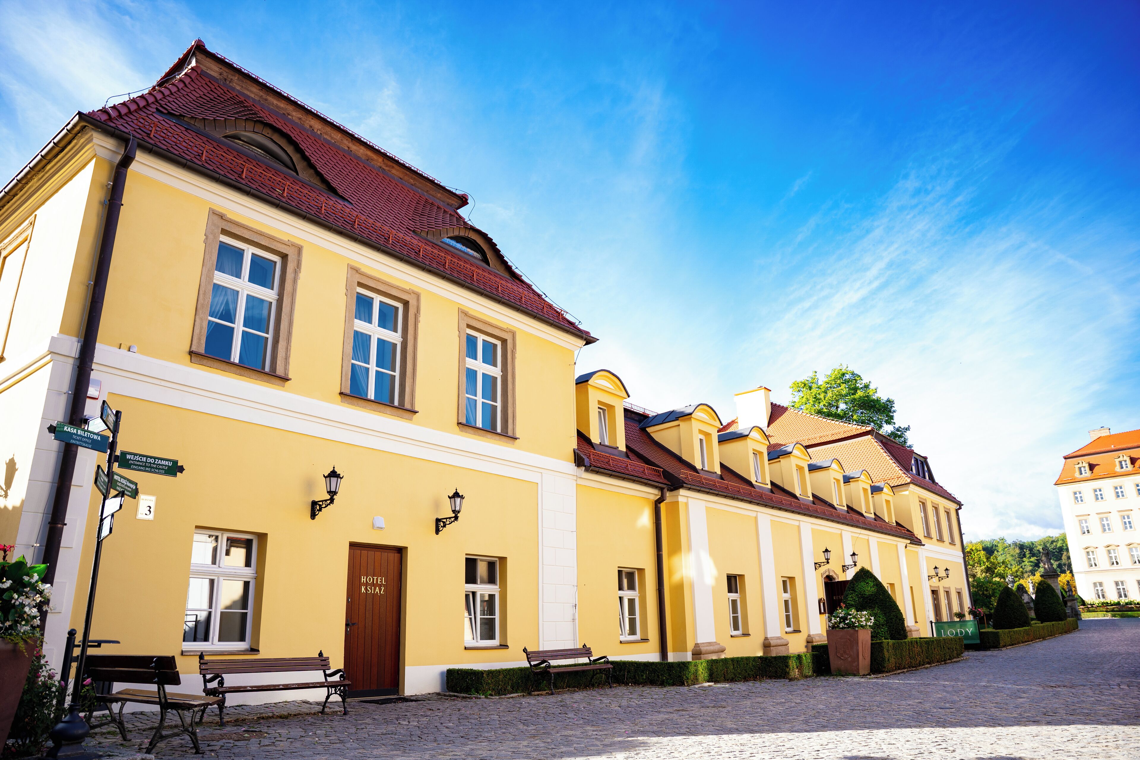 Um edifício amarelo com uma porta castanha com a placa "HOTEL KSIÅA".
