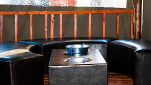 Um espaço de canto com assentos, uma mesa pequena e um objeto azul sobre ela.