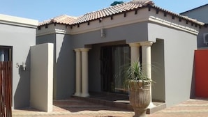Uma casa moderna com telhado em telhas, varanda coberta com colunas e um vaso com planta.