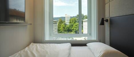 Quarto moderno com uma janela grande, uma cama, uma mesinha de cabeceira e um lustre.