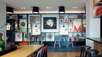 Um interior moderno com uma mesa de madeira, banquetas de bar, uma estante e uma grande obra de arte emoldurada.