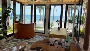 Quarto com vista para o mar, uma mesa de madeira, um banco e uma planta em vaso.