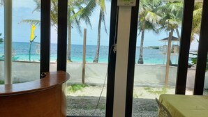 Quarto com vista para a praia, com uma mesa e um banco.