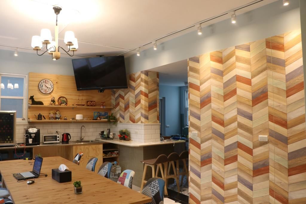 Uma cozinha moderna com uma mesa de jantar de madeira, cadeiras e uma TV fixada na parede.