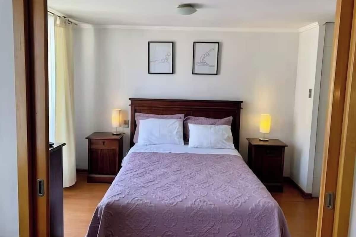 Um quarto com uma cama grande, duas mesas de cabeceira com abajures e duas quadros na parede.