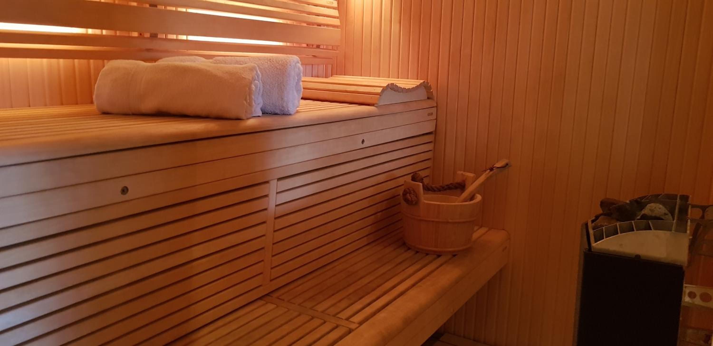 Uma sauna com bancos de madeira, aquecedor e um balde de madeira.