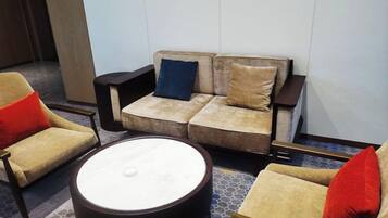 Uma área de estar com um sofá, duas poltronas e uma mesa redonda.
