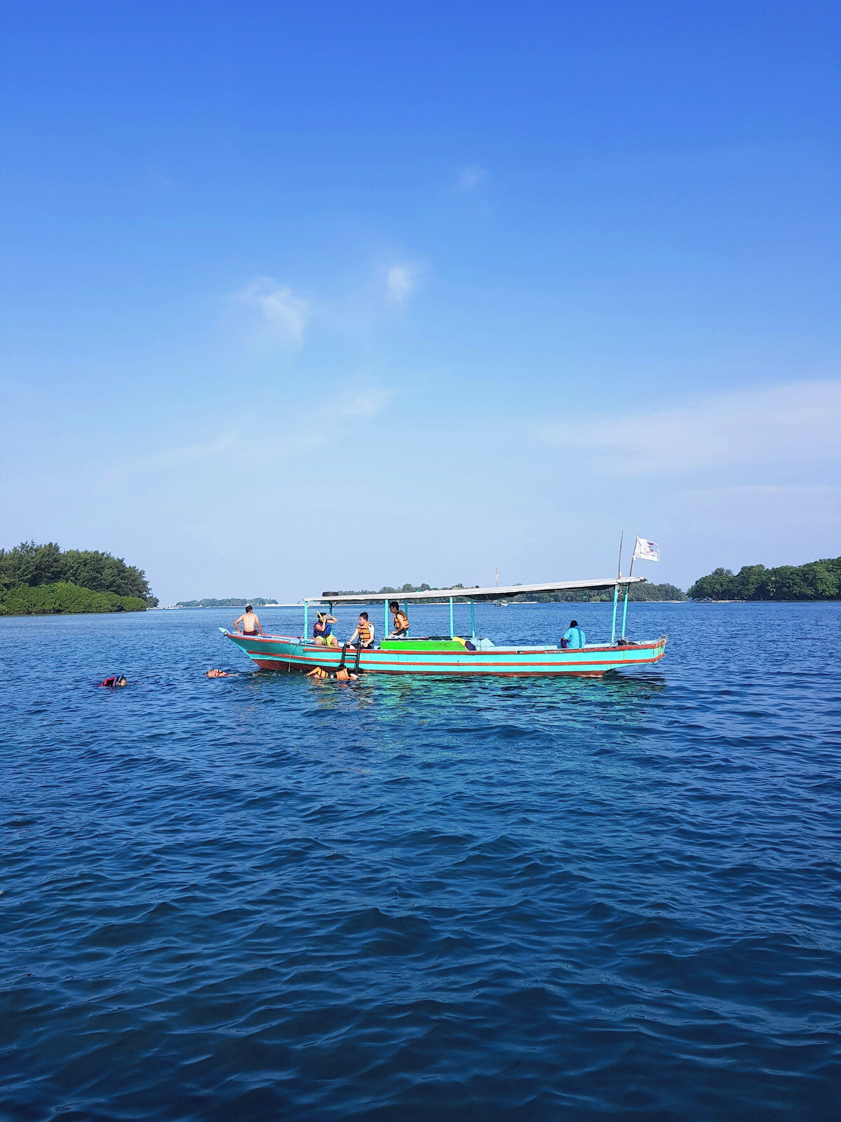 Um barco com passageiros em águas calmas, cercado por vegetação.