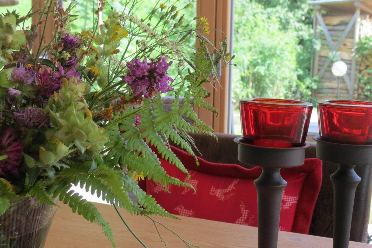 Mesa com arranjo floral e dois castiçais vermelhos.