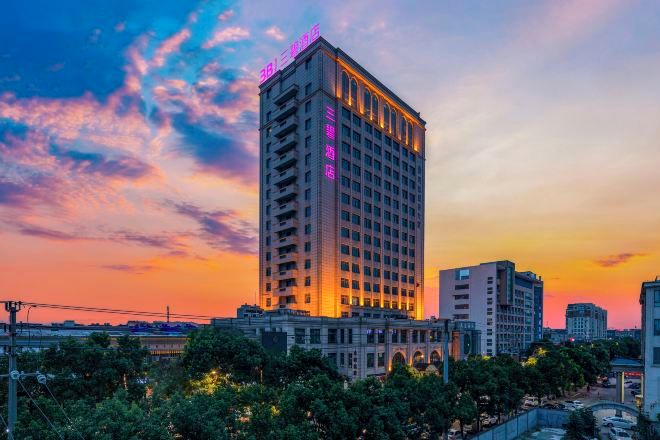 Um hotel moderno com vários andares, uma entrada imponente e vista para a paisagem urbana ao redor.