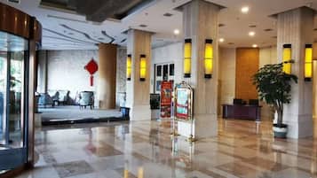 Um saguão de hotel com balcão de recepção, área de estar e palco.